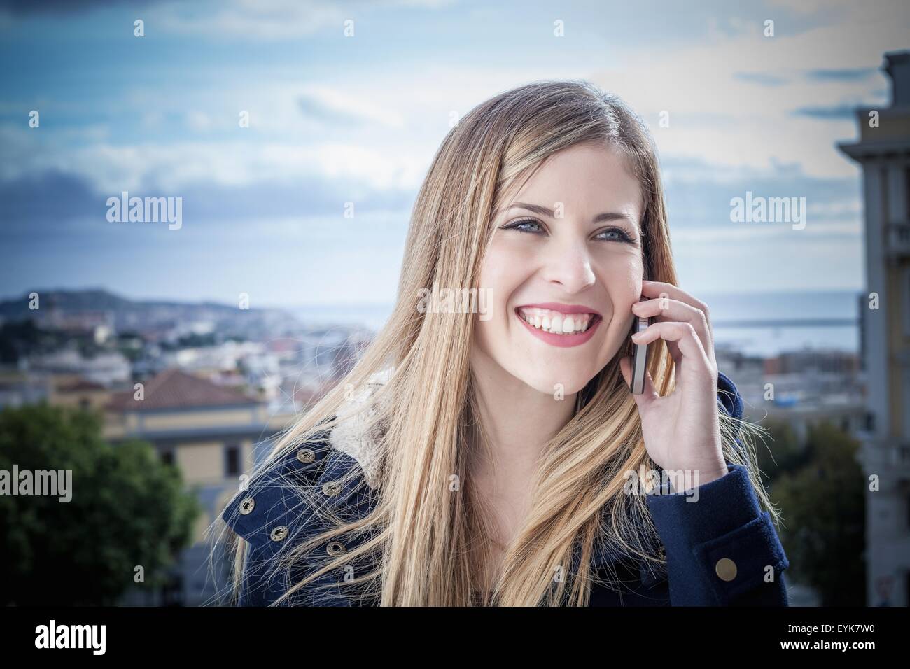 Young woman on rooftop talking on smartphone, Cagliari, Sardinia, Italy ...