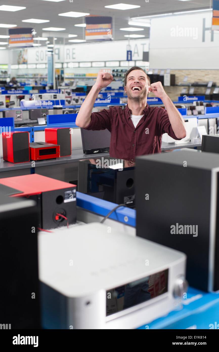 Male shopper celebrating finding product in electronics store Stock ...