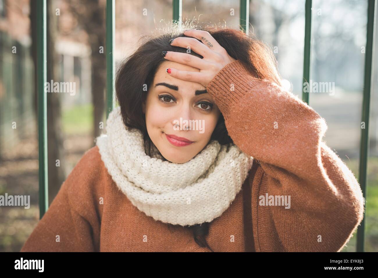 Portrait of young woman with hand on forehead in park Stock Photo - Alamy