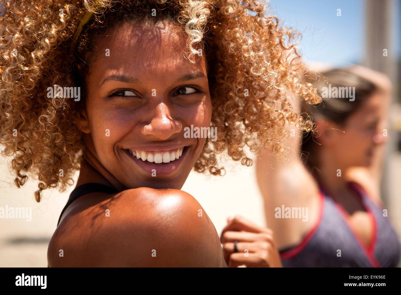 Young woman with curly hair looking over shoulder Stock Photo - Alamy