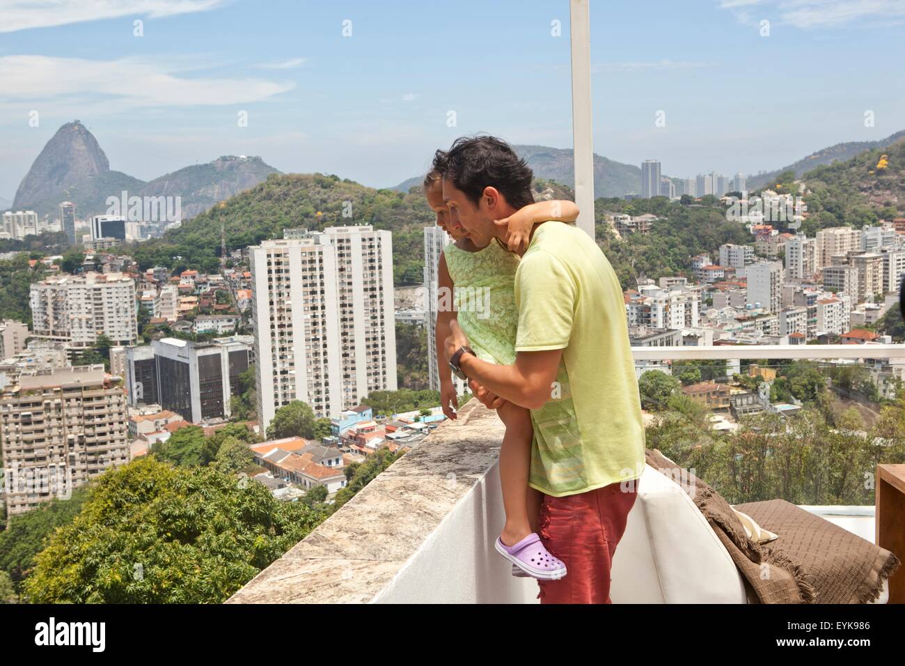 Father and daughter looking over balcony at view, Rio de Janeiro ...