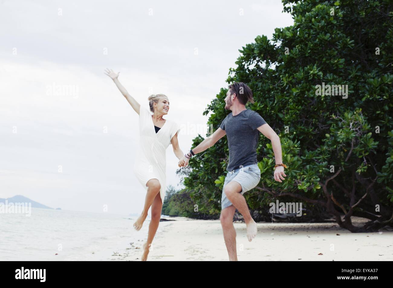 Young couple jumping and fooling around on beach, Kradan, Thailand ...