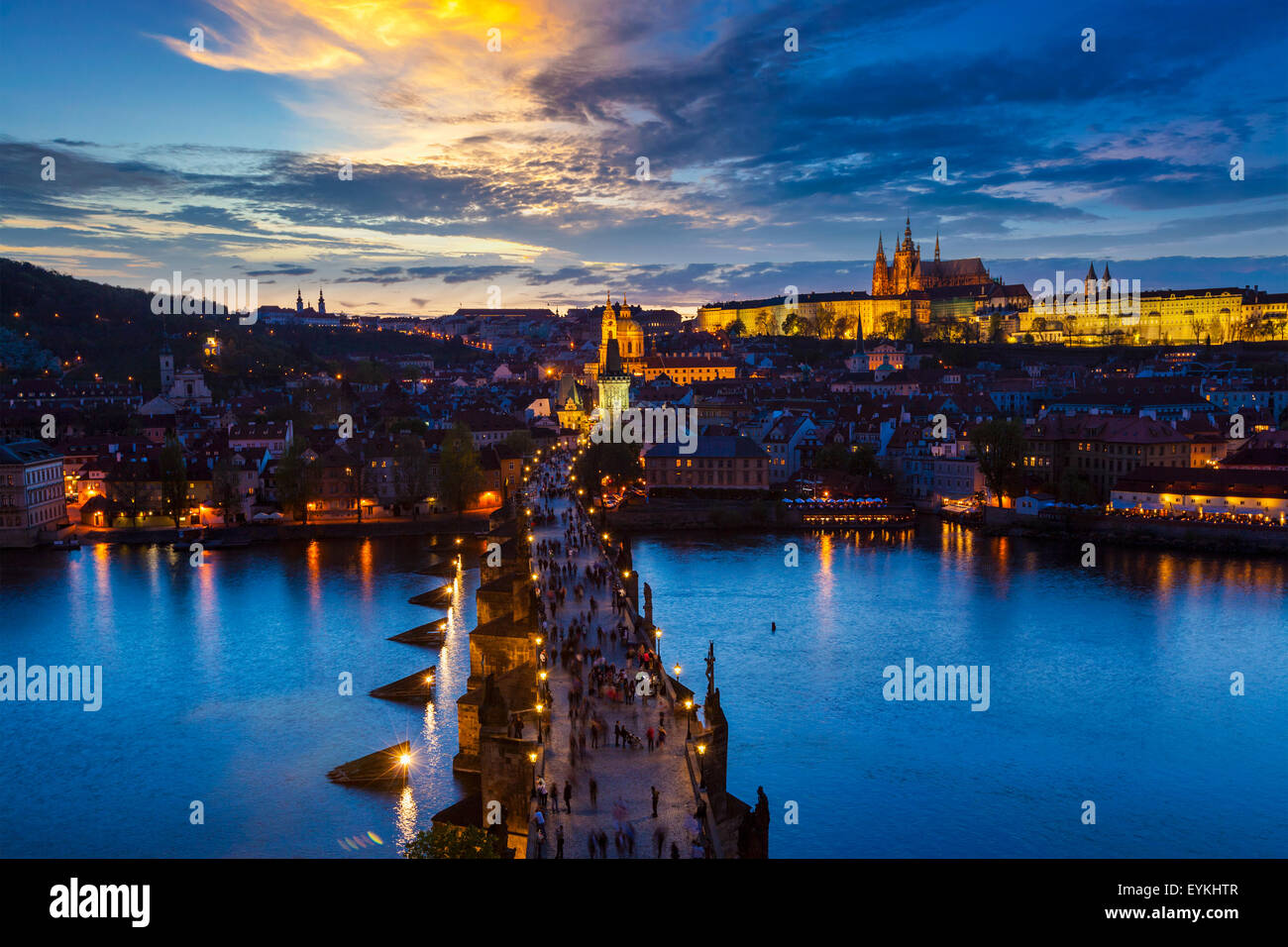 Aerial view of illuminated Prague castle and Charles Bridge with tourist crowd over Vltava river ...
