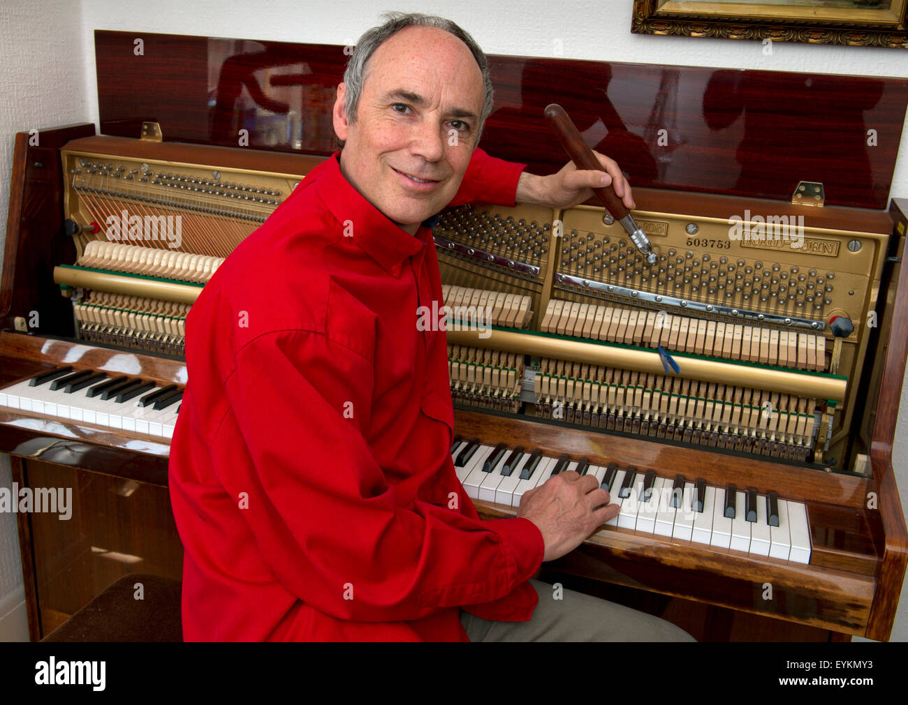 Piano tuner Chris Jewell working on an upright piano,a musical ...