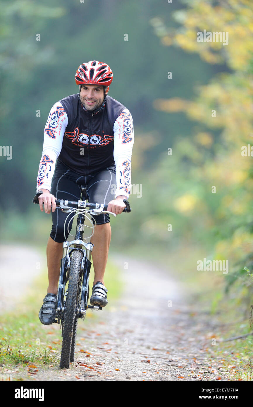 Man is riding mountainbike, looking at camera Stock Photo - Alamy