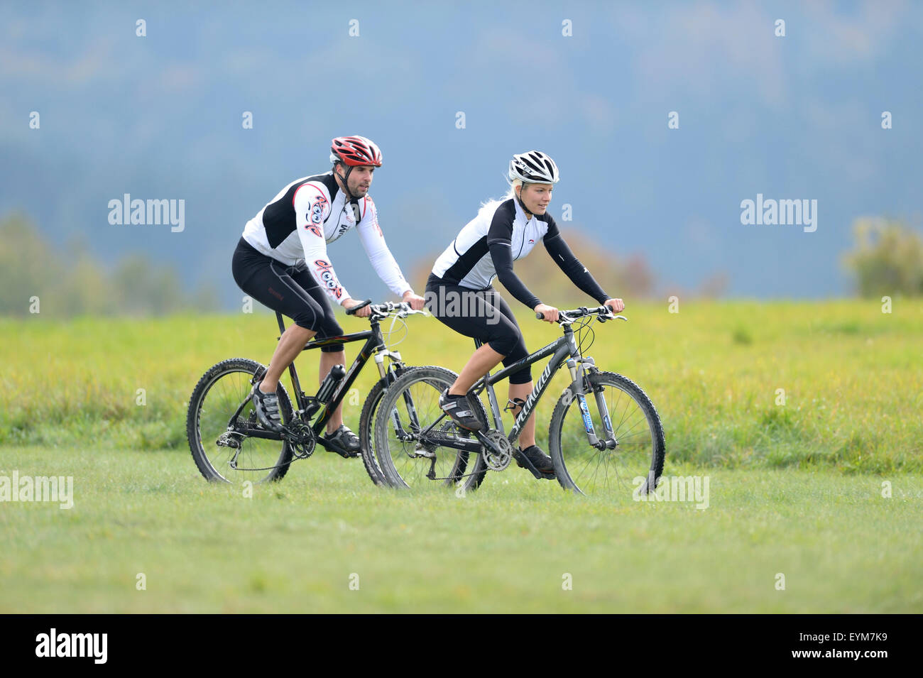 Couple is riding mountainbikes on a meadow Stock Photo - Alamy