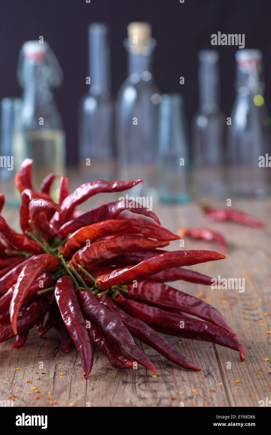 Dry chilli pods on wooden table, bottles before dark background Stock ...