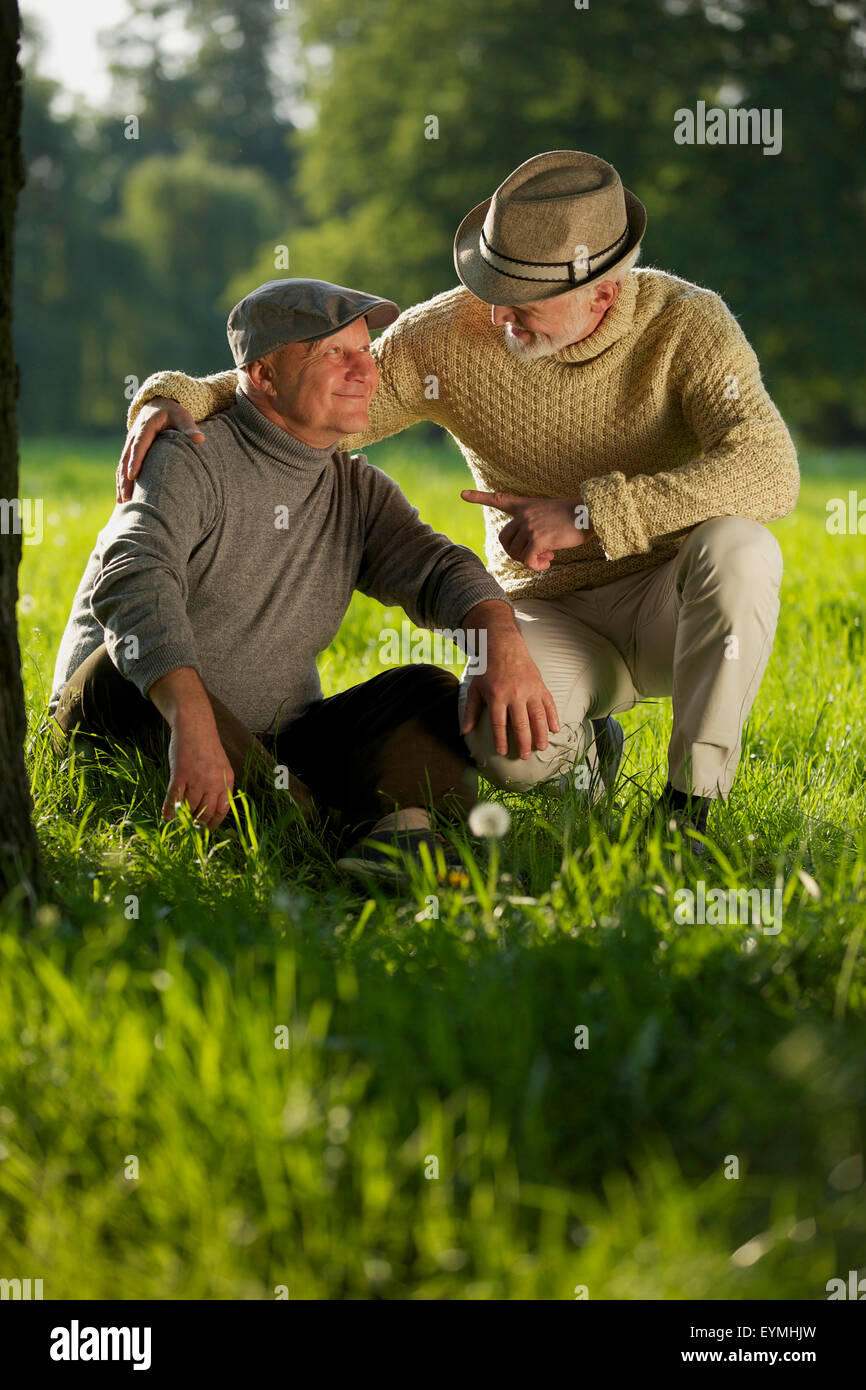 Two senior citizens, meadow, sitting, talking aboution, smiling ...