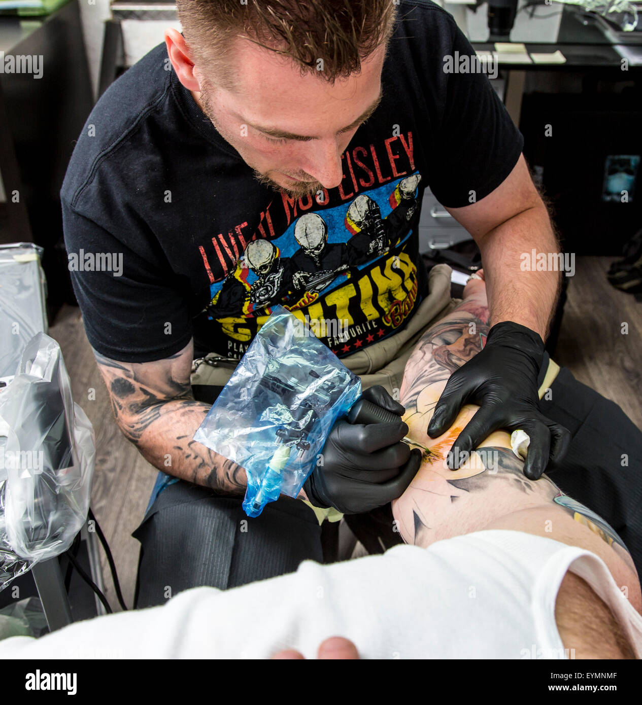 Tattoo studio, tattoo artist at work with the tattooing machine ...
