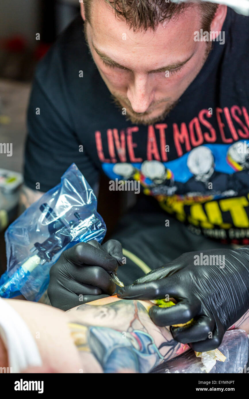 Tattoo studio, tattoo artist at work with the tattooing machine ...