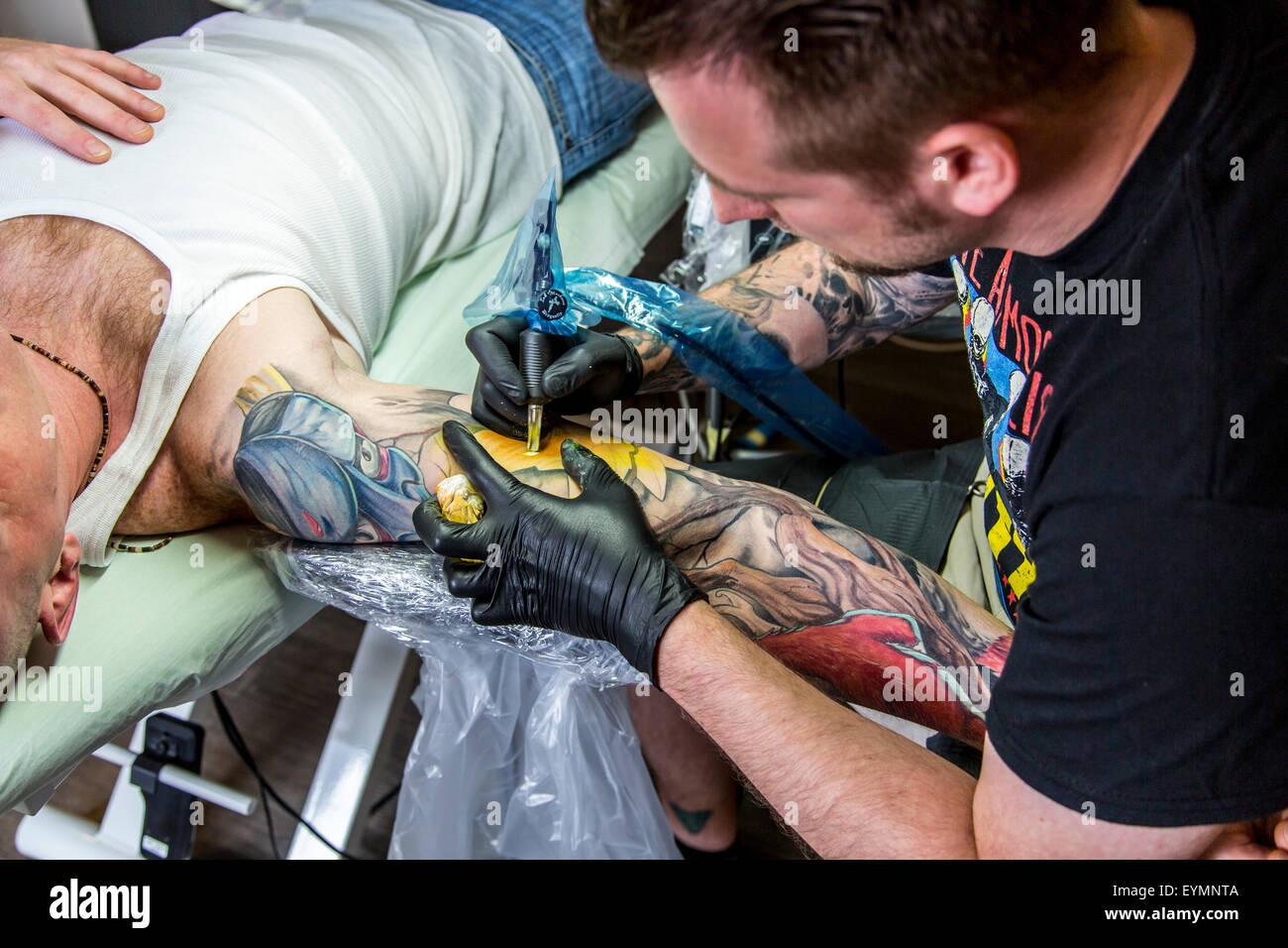 Tattoo studio, tattoo artist at work with the tattooing machine ...