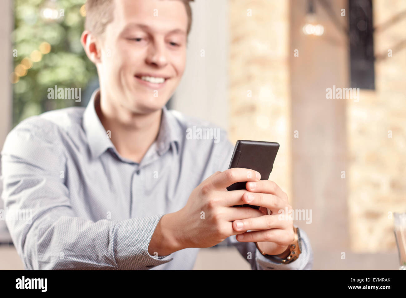 Handsome guy using mobile phone in cafe Stock Photo - Alamy