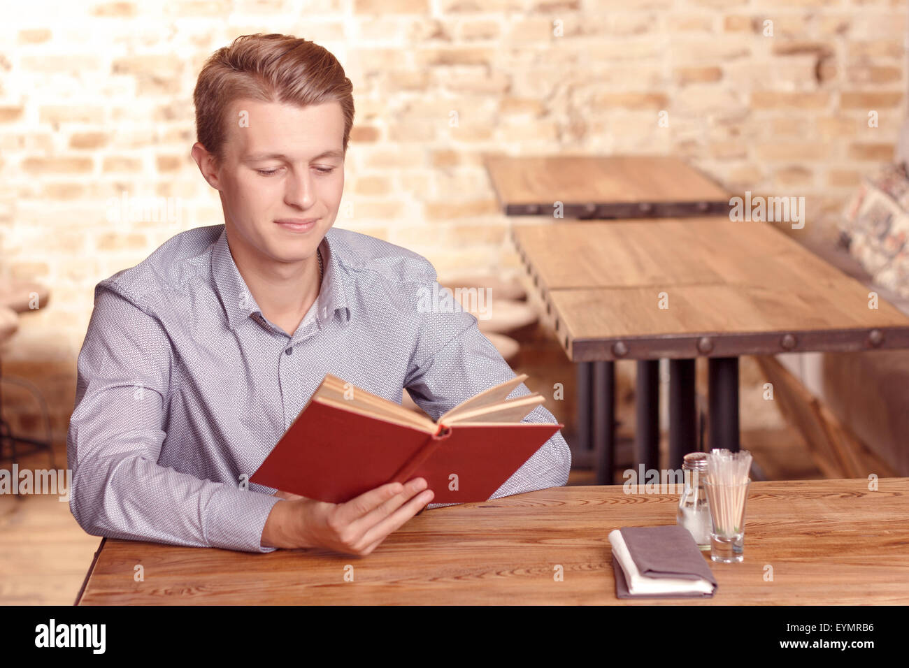 Young handsome man reading book in cafe Stock Photo - Alamy