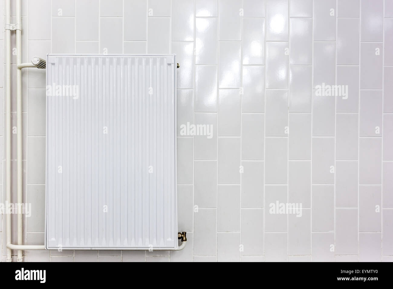 At the white tiles hang an radiator and tubes Stock Photo - Alamy