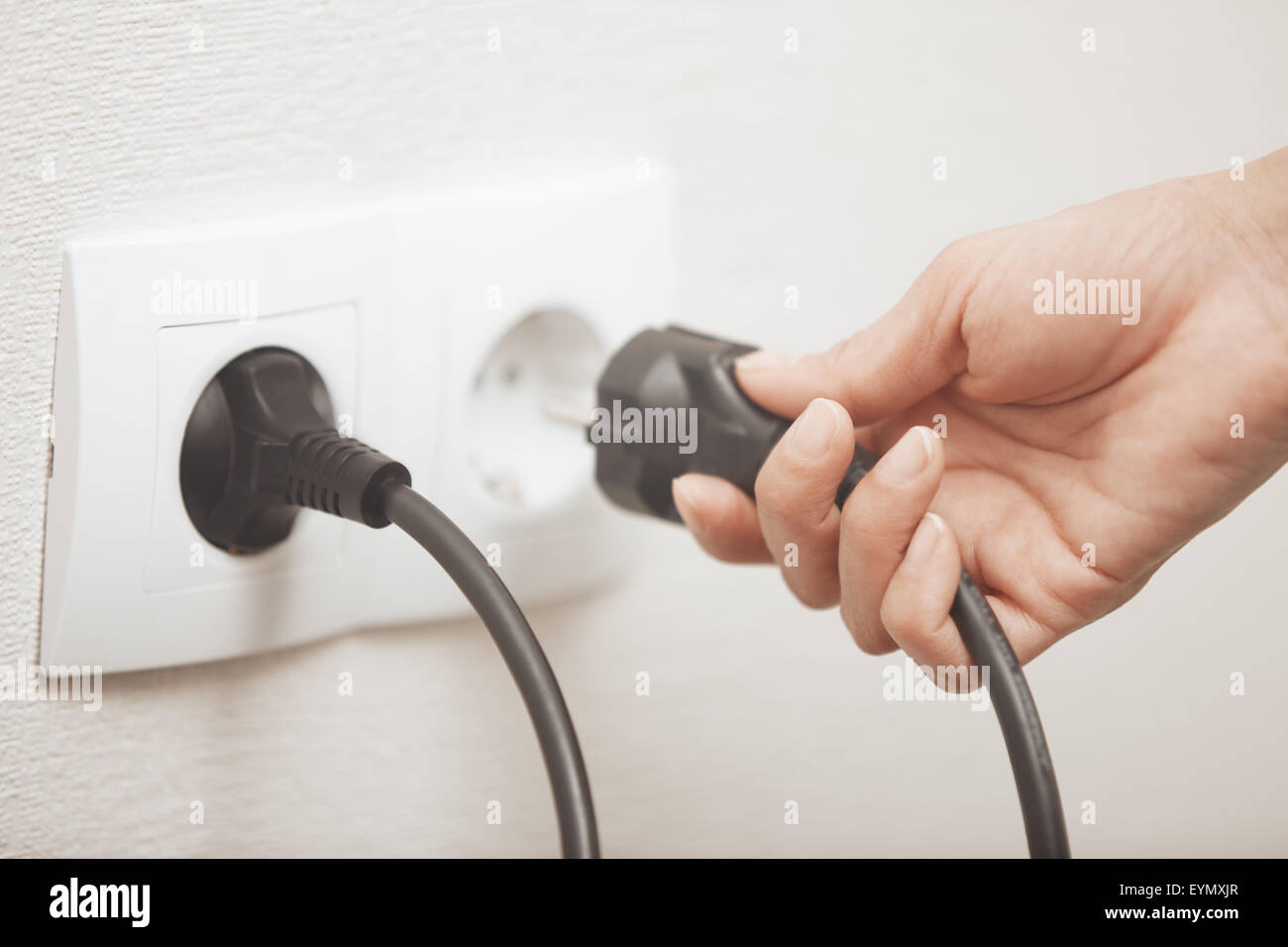 Woman plugging cable to the electric outlet Stock Photo - Alamy