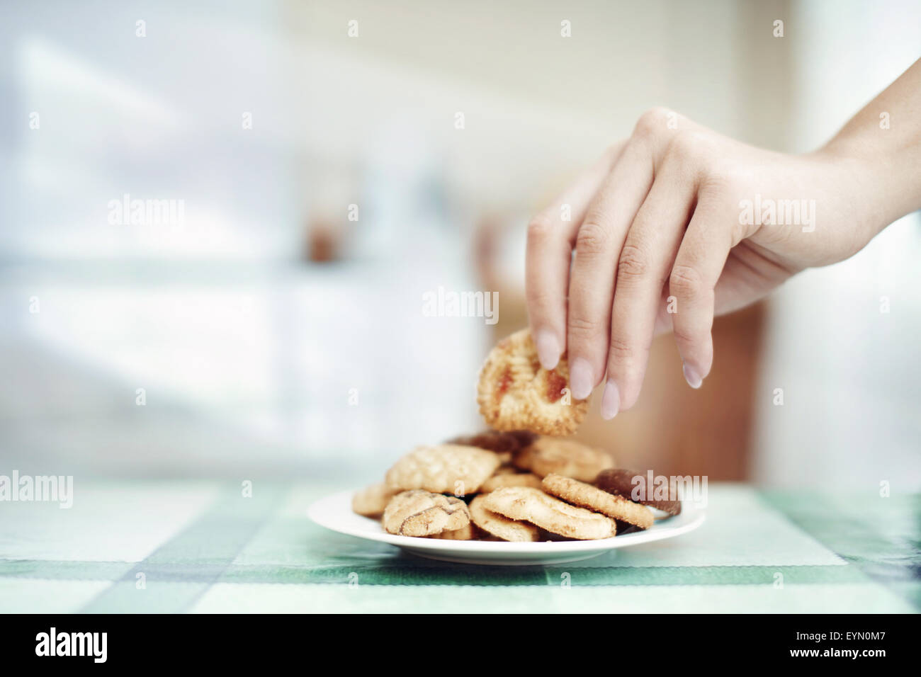 Human hand taking cookie in plate on a table Stock Photo - Alamy