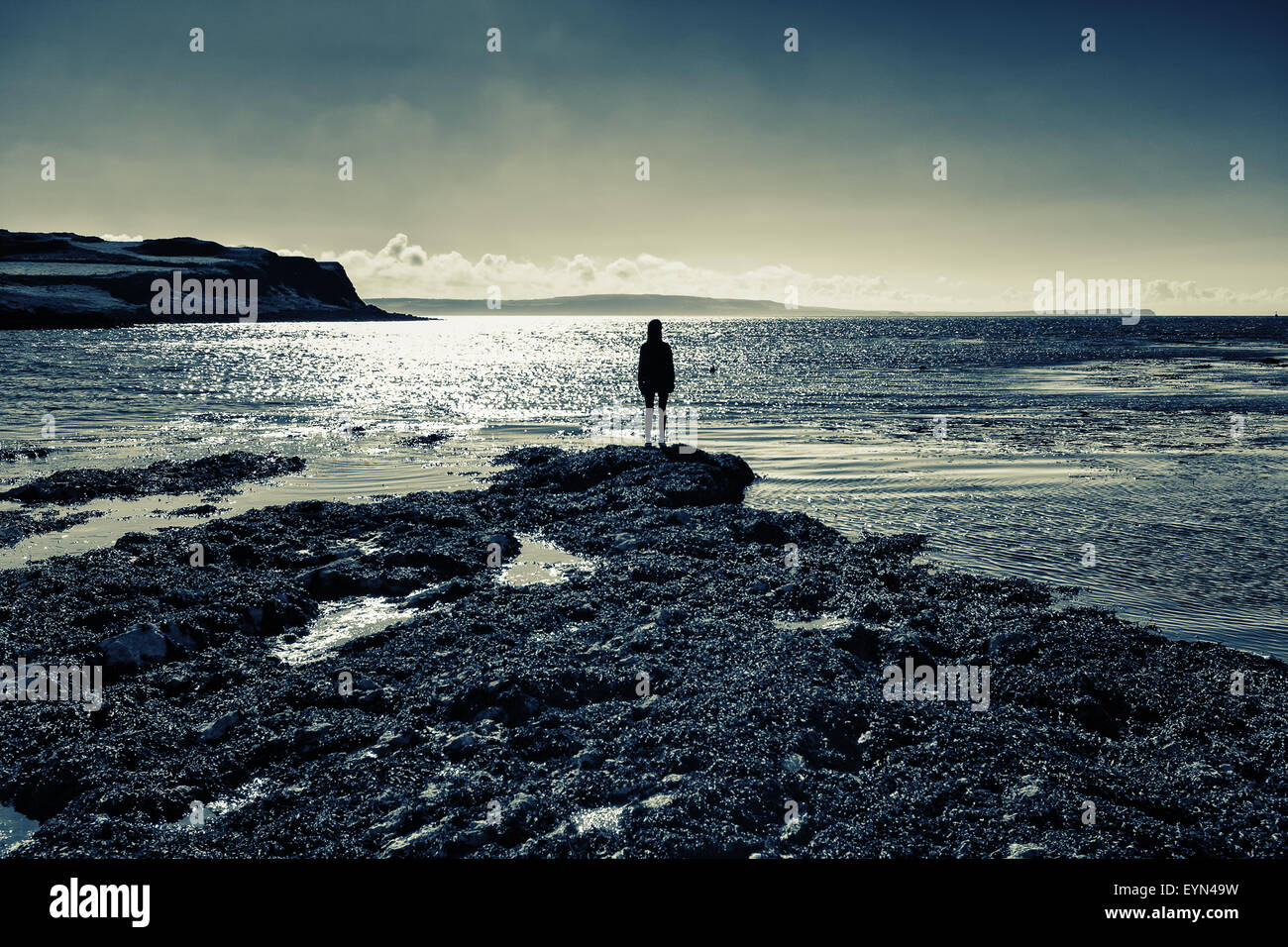 Standing alone by the sea, blue filtered image Stock Photo - Alamy