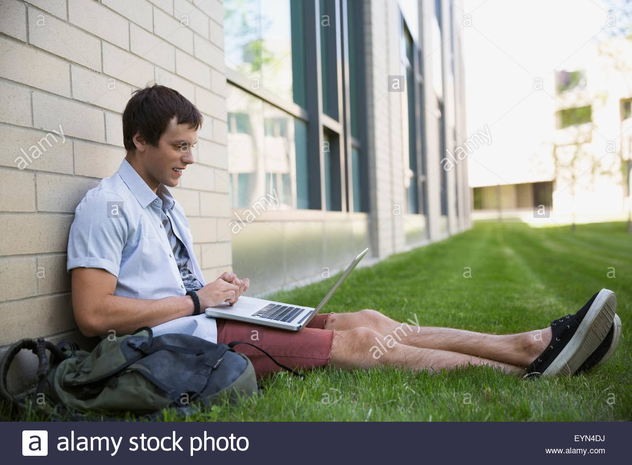 College student using laptop on campus lawn Stock Photo - Alamy