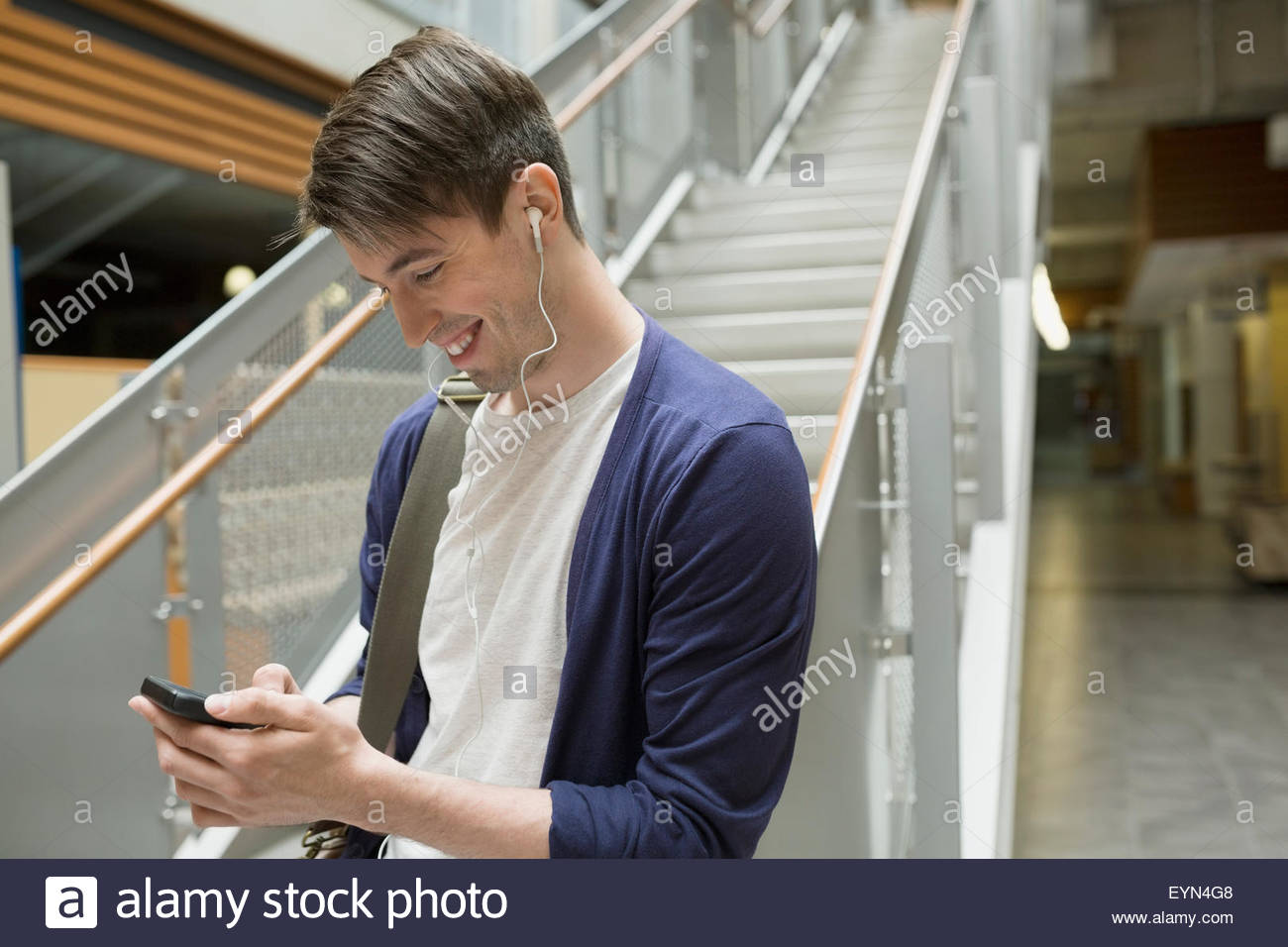 Smiling college student using mp3 player at stairs Stock Photo - Alamy