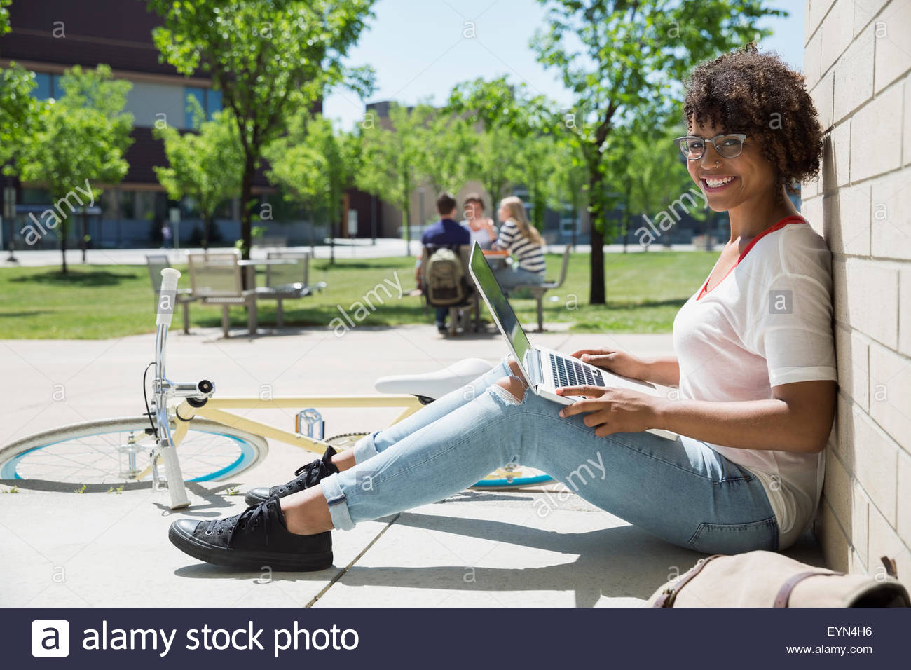 Portrait college student using laptop on sunny campus Stock Photo - Alamy