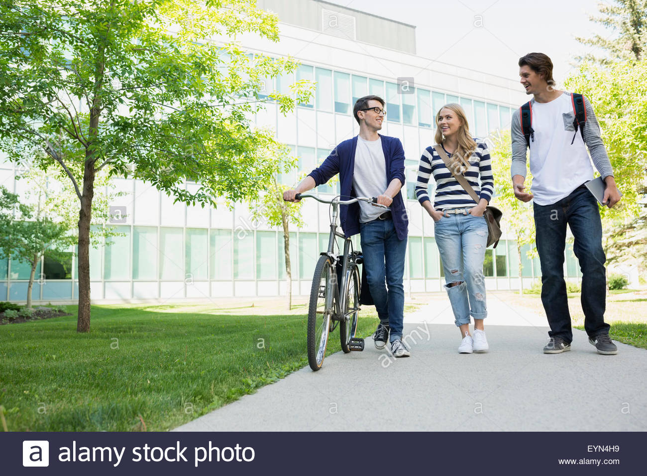 College students with bicycle walking on campus sidewalk Stock Photo ...