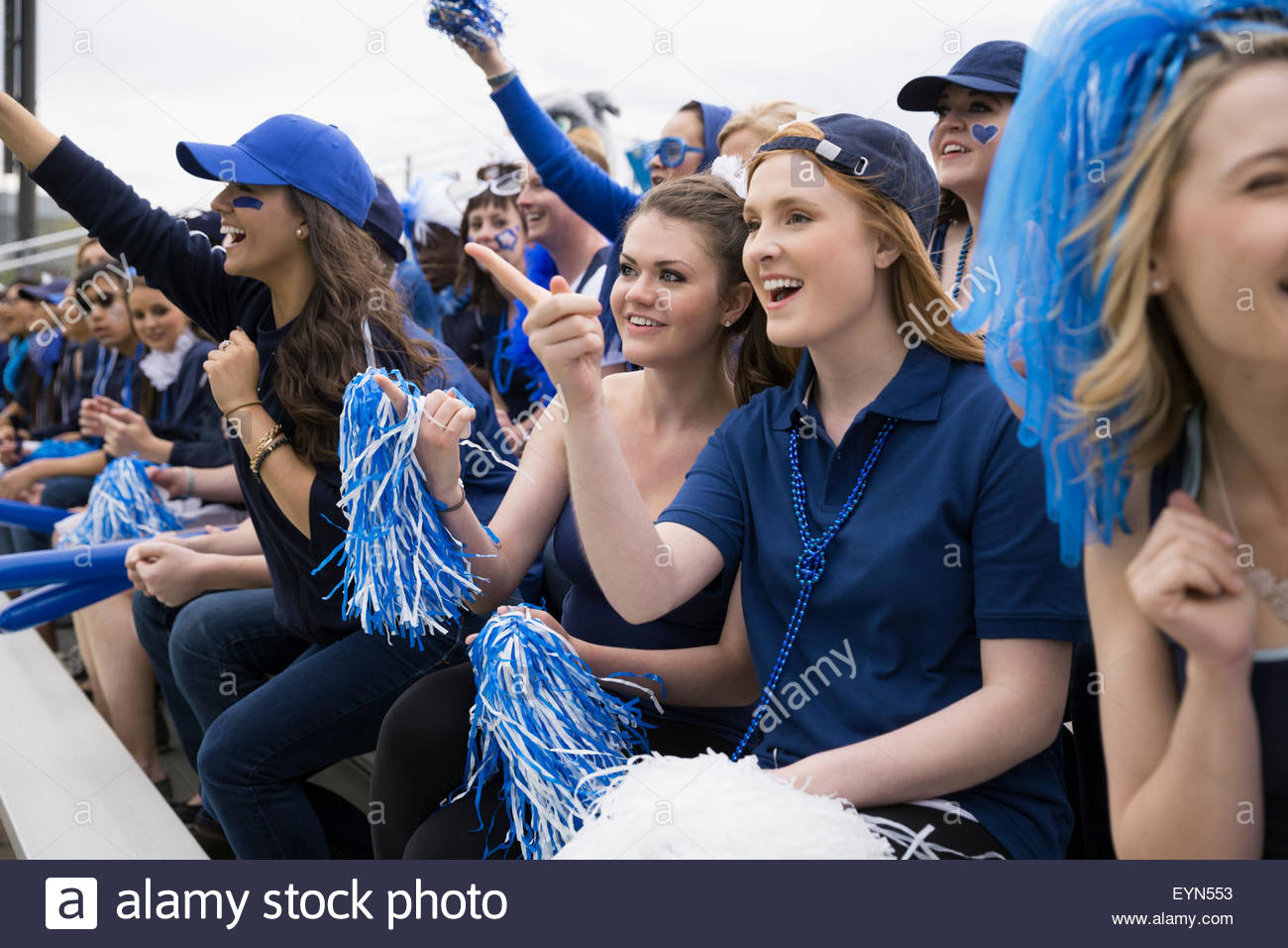 Smiling fans in blue pointing bleachers sports event Stock Photo - Alamy