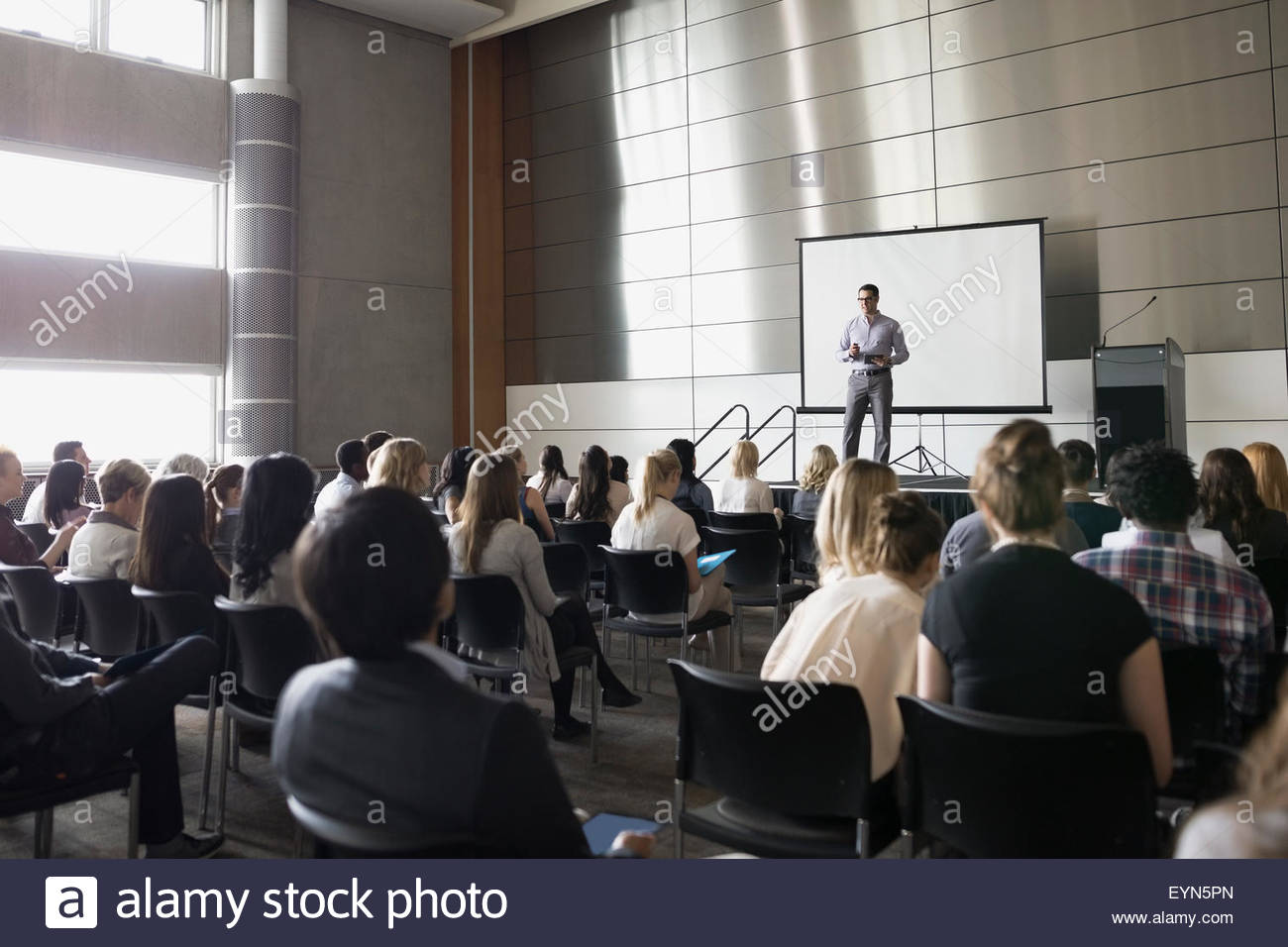 Students in auditorium audience watching professor on stage Stock Photo ...