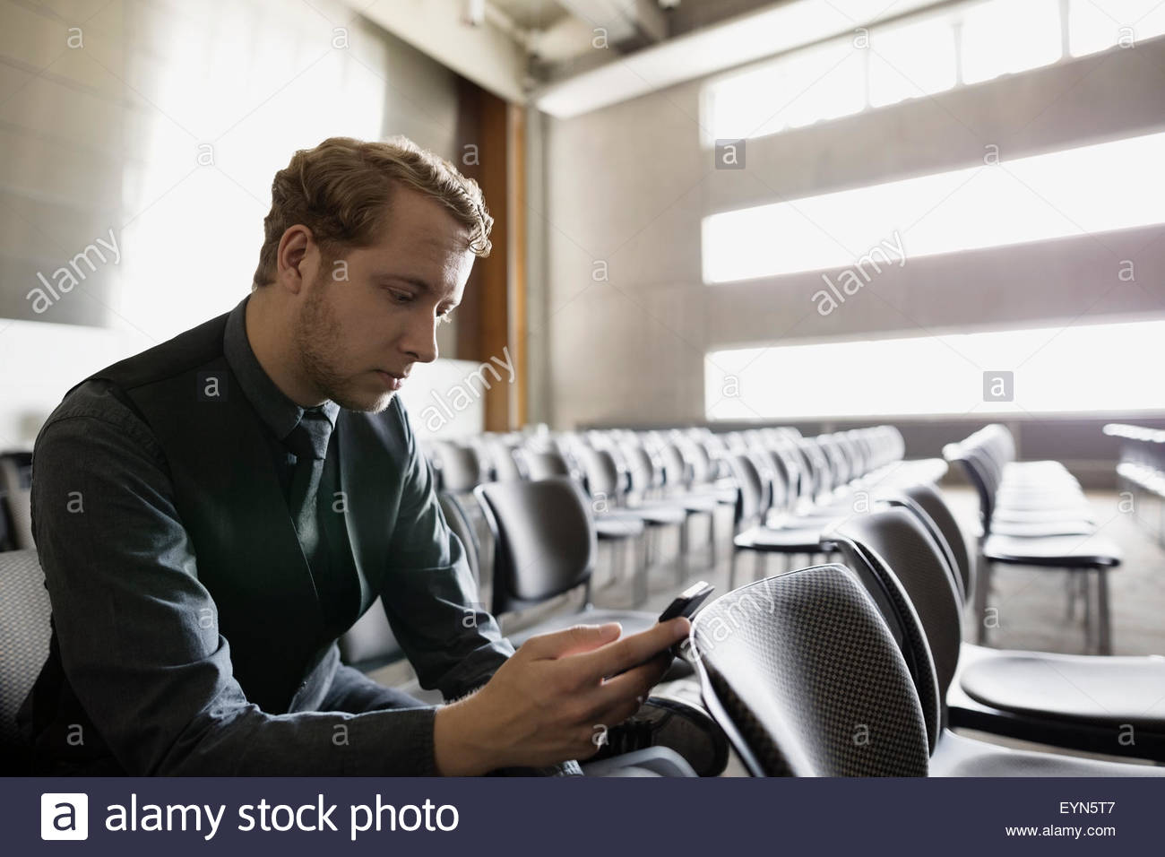 Man texting with cell phone in empty auditorium Stock Photo - Alamy