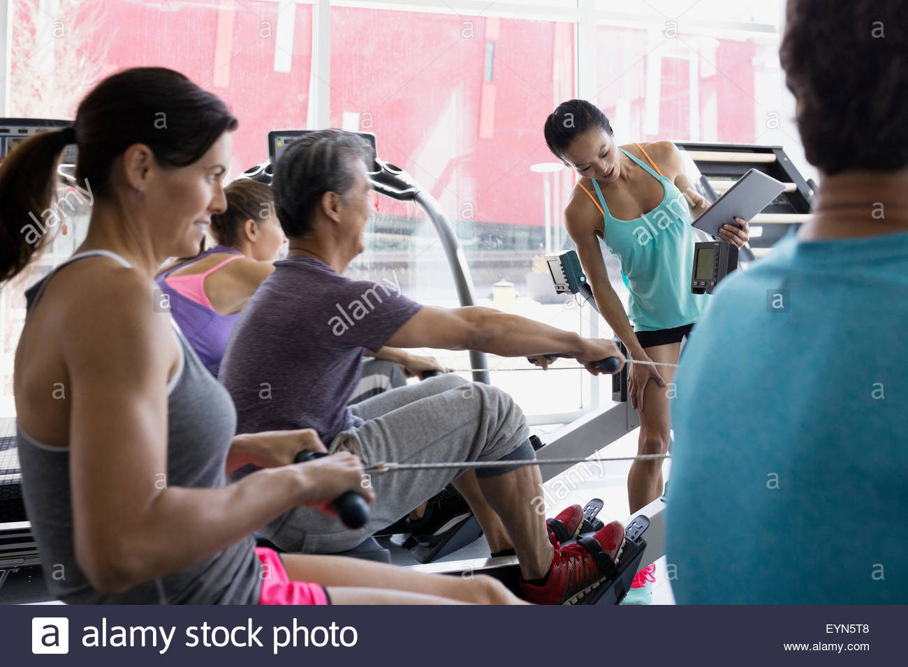 Fitness instructor with digital tablet guiding rowing class Stock Photo ...