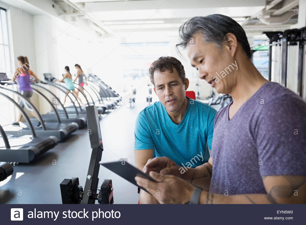 Personal trainer digital tablet talking to man gym Stock Photo - Alamy