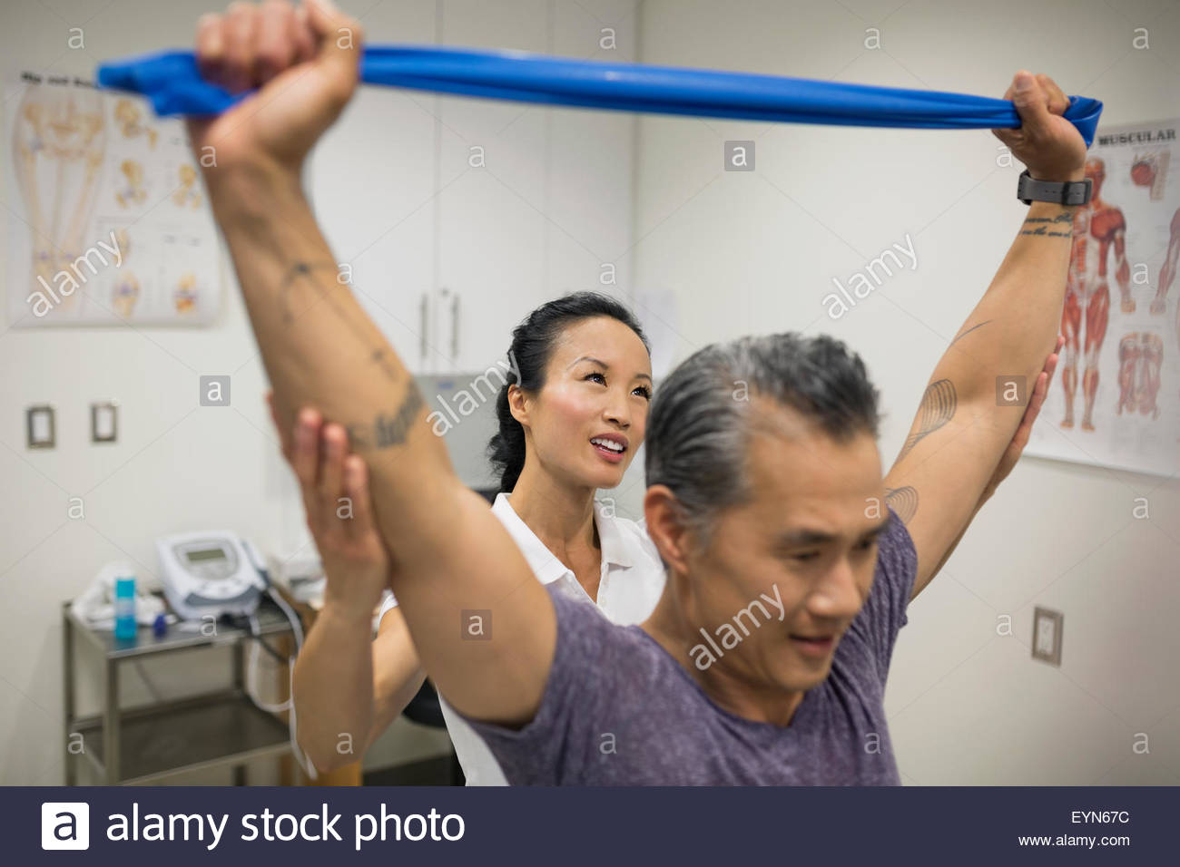 Physical therapist guiding patient pulling resistance band Stock Photo ...