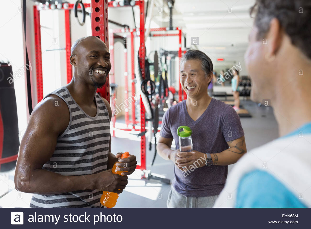 Smiling men with water bottles talking at gym Stock Photo - Alamy