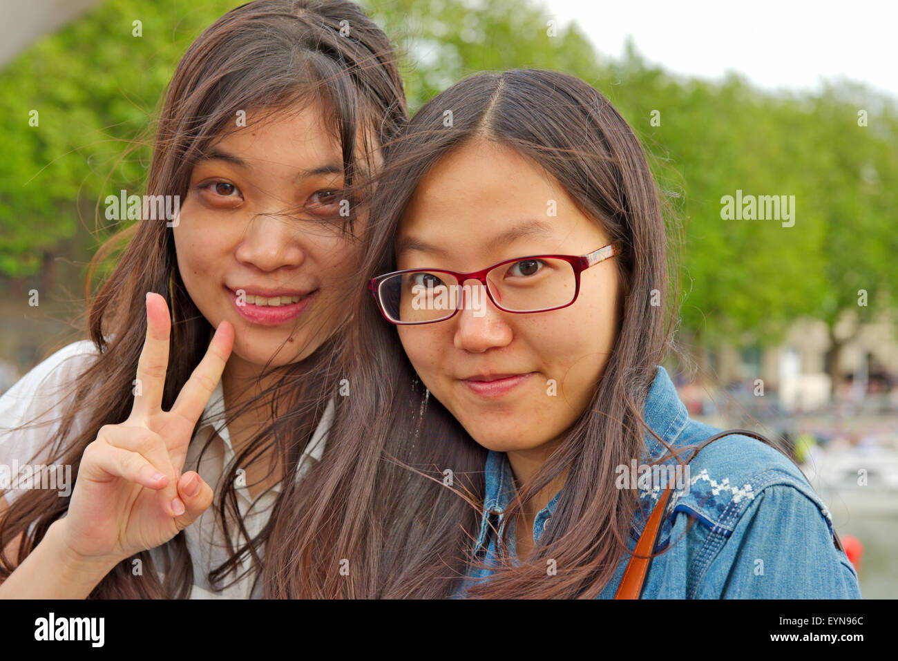 Portrait of two attractive young Asian women, one giving “V” sign Stock ...