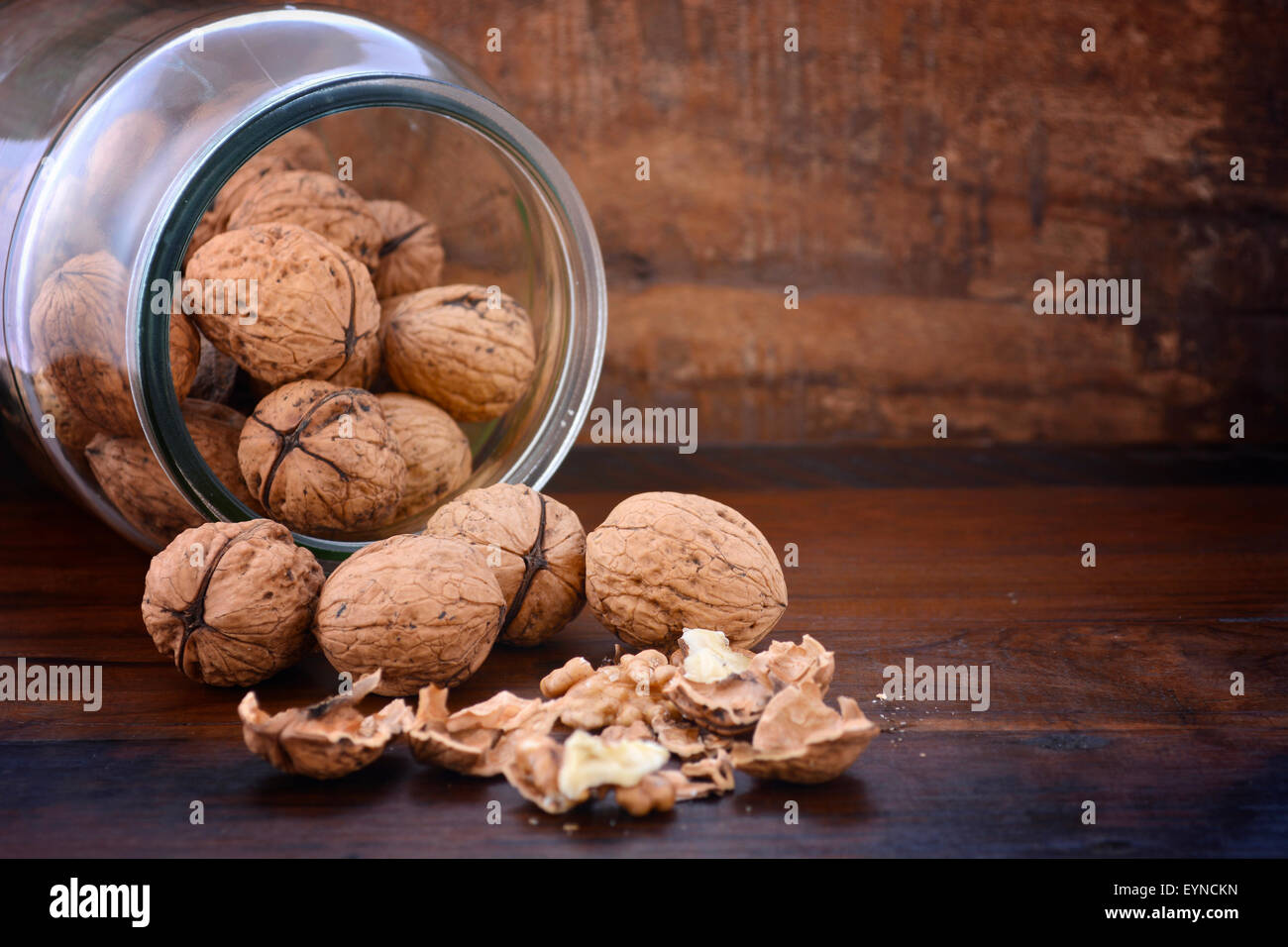 Fresh walnuts in shells falling out of glass jar on rustic dark wood ...