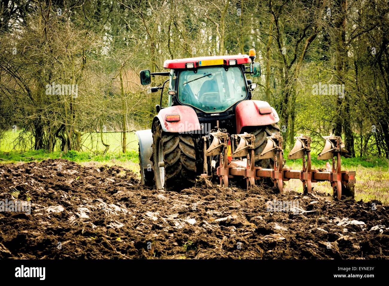 Tractor turning the earth in a field in springtime Stock Photo - Alamy