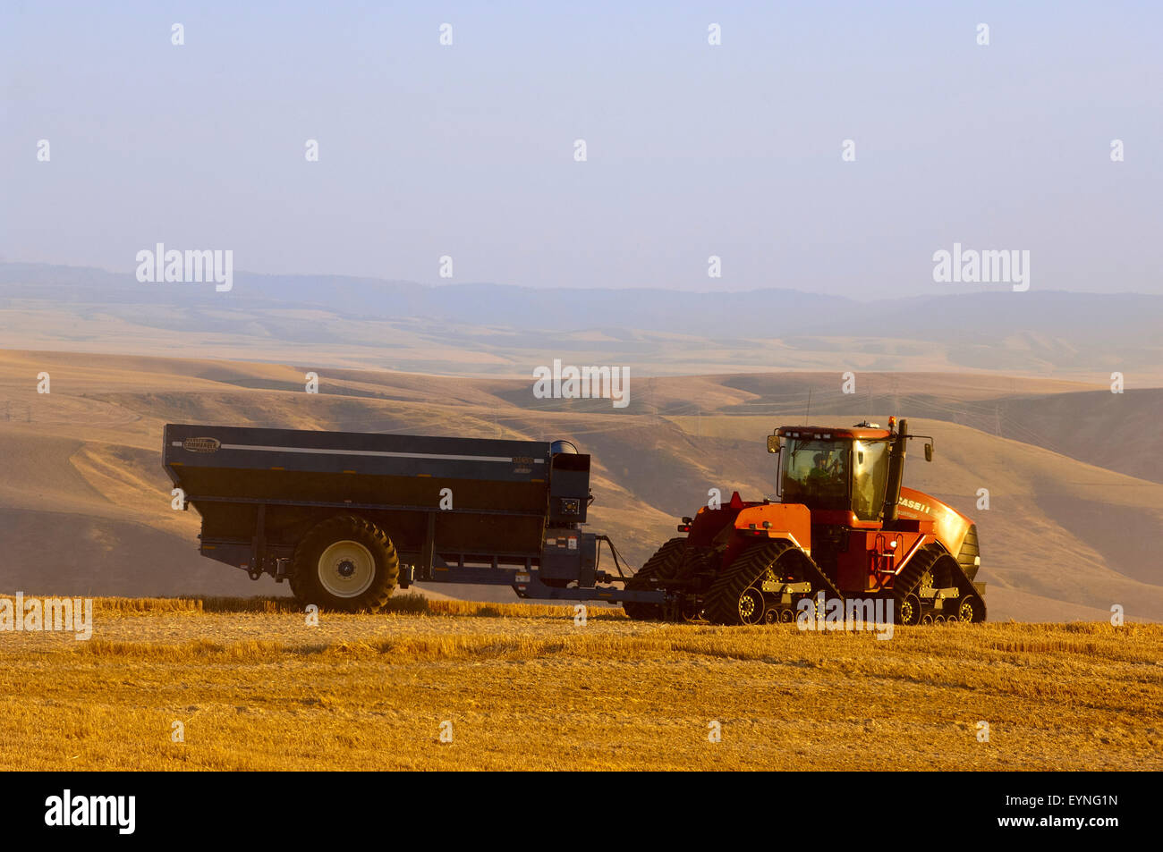 Tractor pulling grain cart in a grain field during harvest in the ...