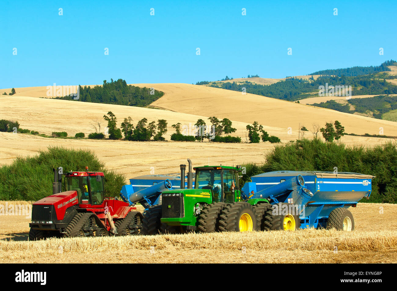 Two tractors pulling grain carts waiting to unload combines in the ...
