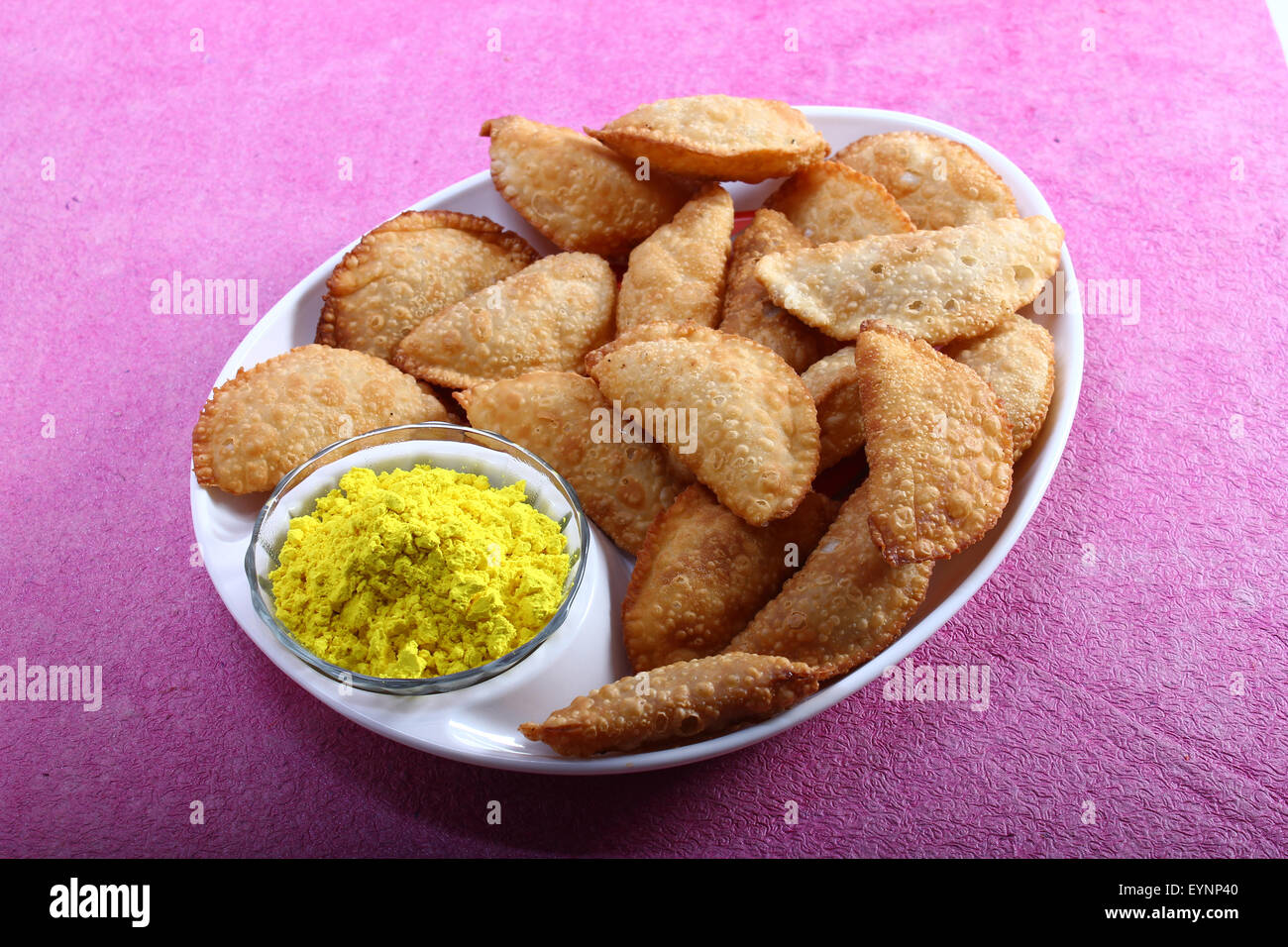 Indian traditional Snack Gujiya served in plate along with Holi color ...