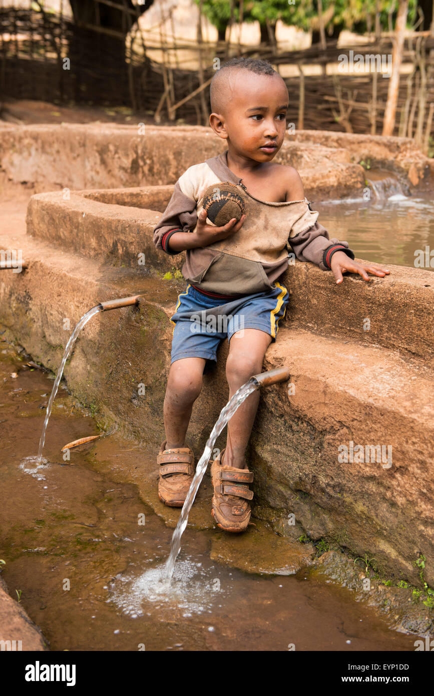 Boy sitting at a water fontain, part of irrigation scheme, Asossa ...