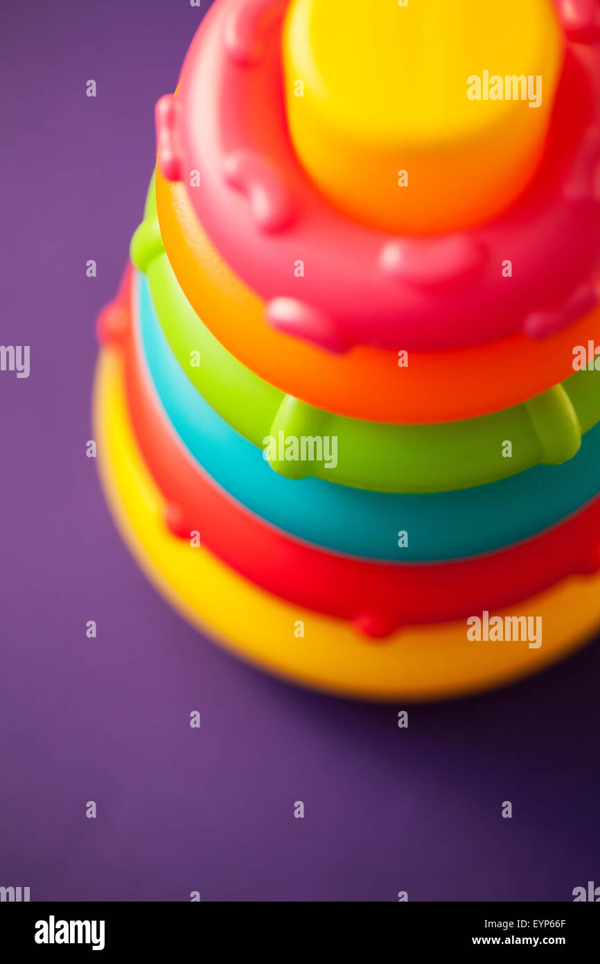 Child's stacking rings toy shot on a purple background. Multi coloured ...