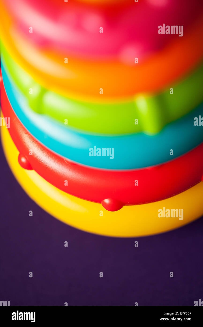 Child's stacking rings toy shot on a purple background. Multi coloured ...