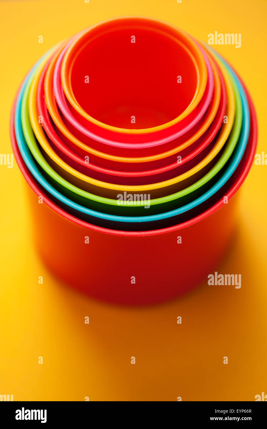 Child's stacking cup toy on a yellow background. Multi colored cups ...