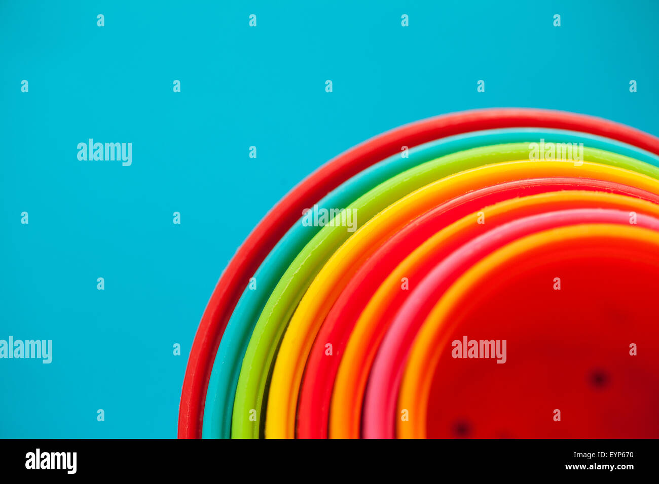 Child's toy stacking cups. Rainbow coloured cups sat on a blue ...