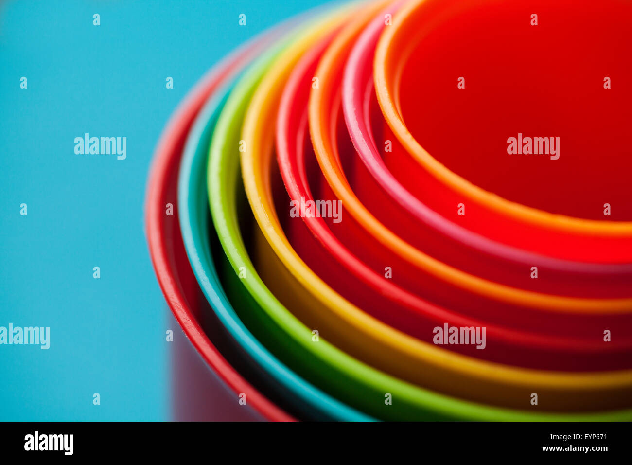 Child's toy stacking cups. Rainbow coloured cups sat on a blue ...