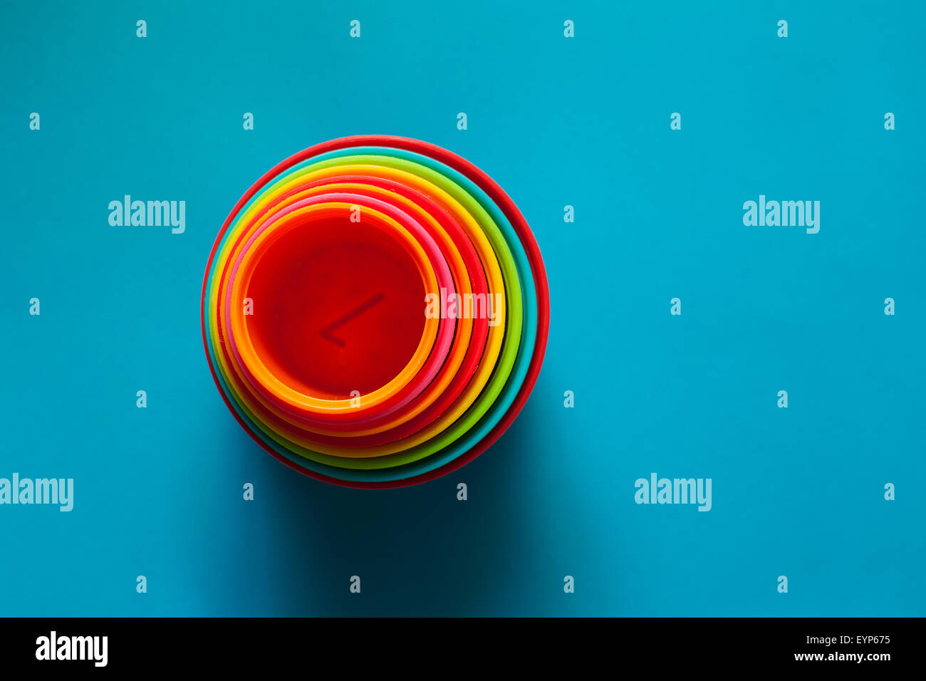 Child's toy stacking cups. Rainbow coloured cups sat on a blue ...