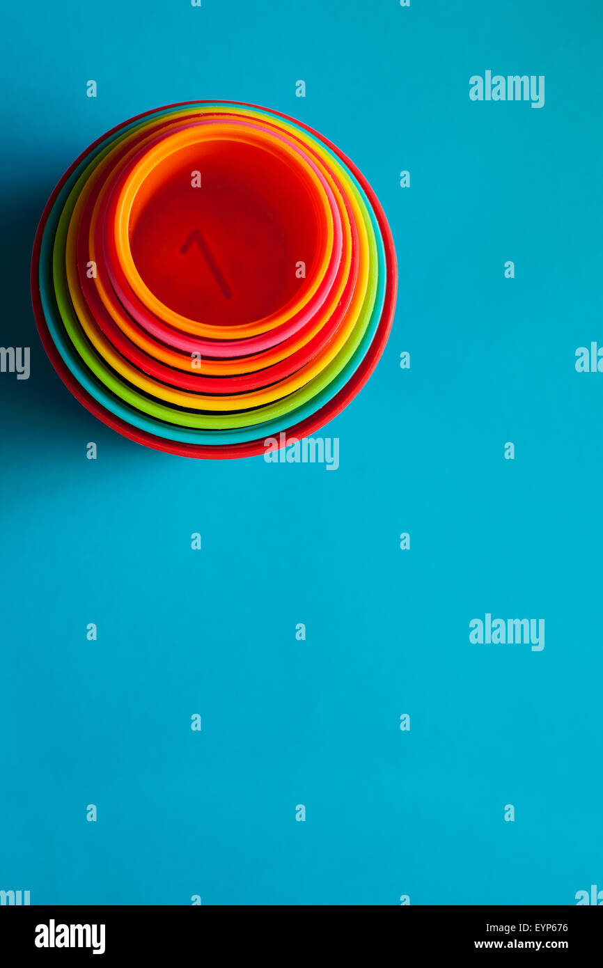 Child's toy stacking cups. Rainbow coloured cups sat on a blue ...