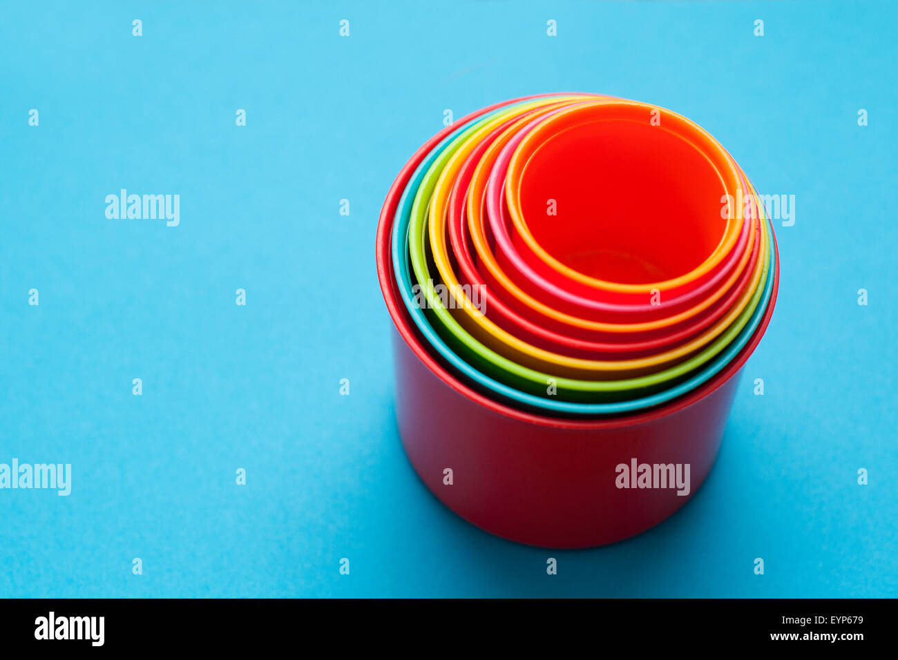 Child's toy stacking cups. Rainbow coloured cups sat on a blue ...