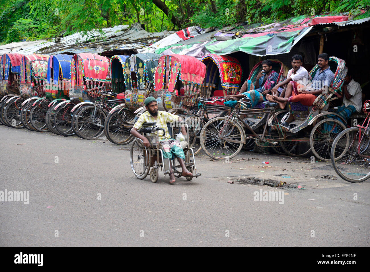 Bangladeshi rickshaw drivers waiting for passengers beside a disable ...