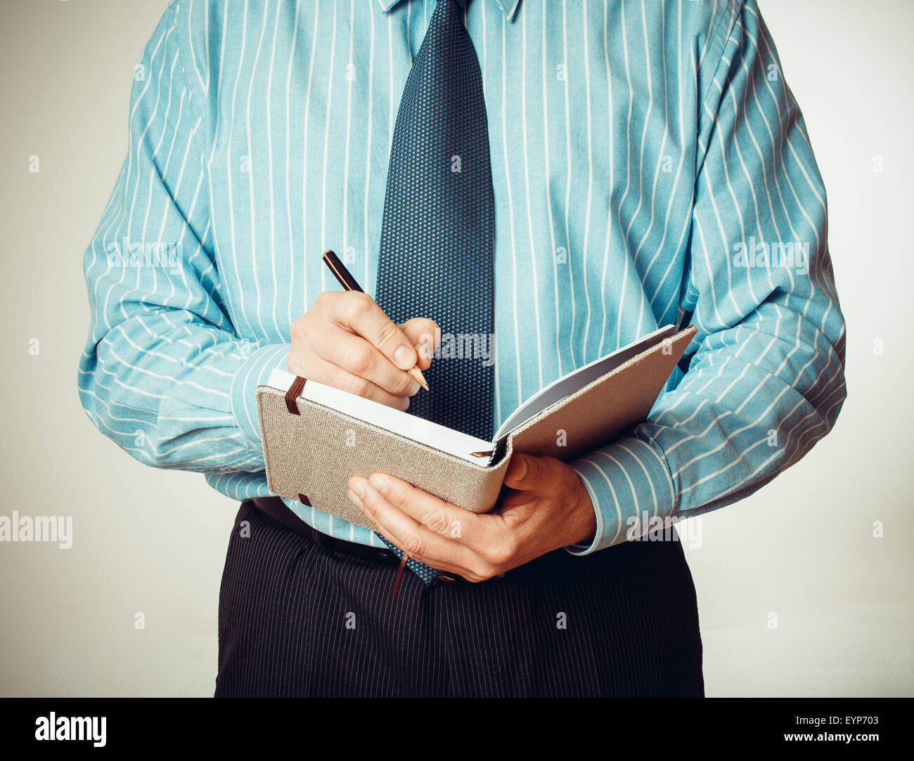 Businessman with notebook and pen writing report Stock Photo - Alamy