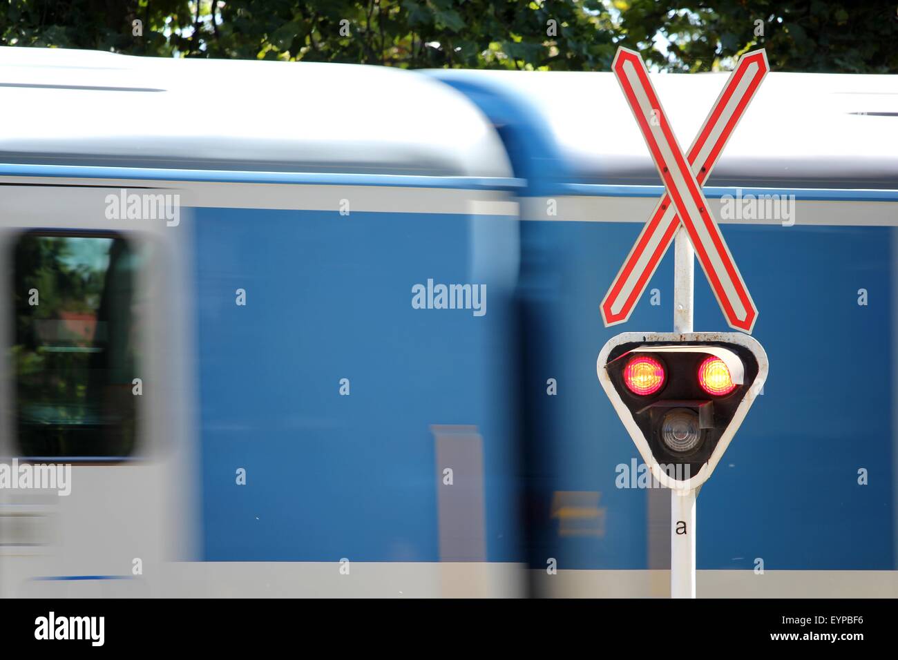red railway crossing signal with a passing train Stock Photo - Alamy